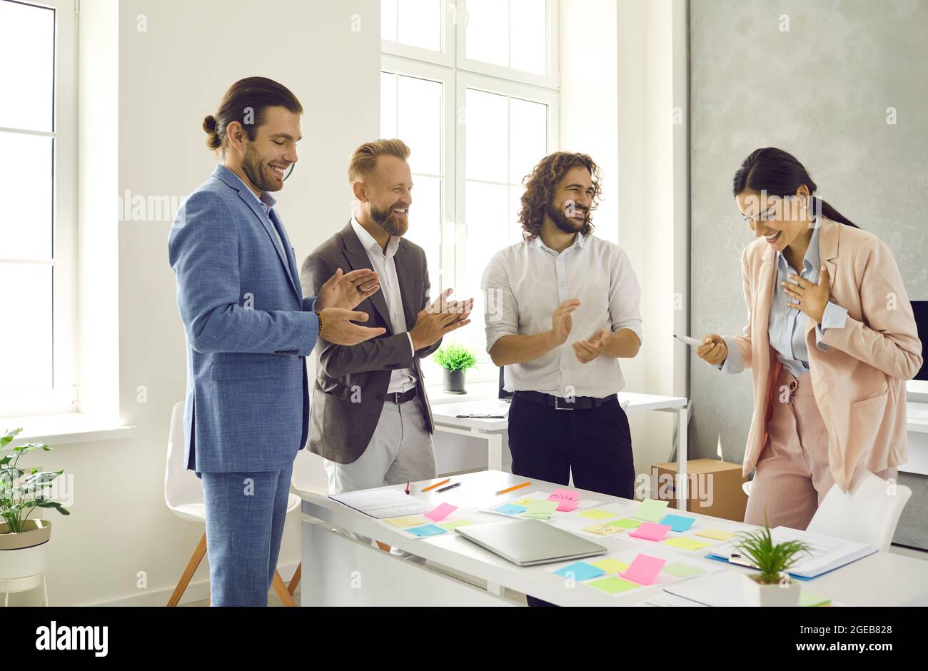 Happy cheerful creative business team applauds their female colleague ...