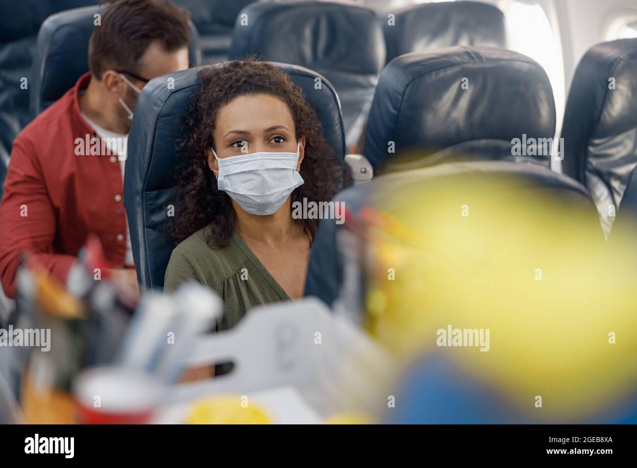 Female passenger wearing protective face mask waiting for stewardess to ...
