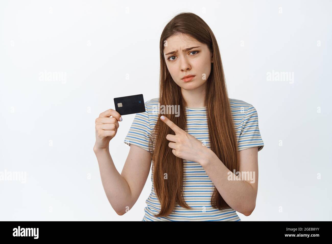 Disappointed woman pointing finger at credit card, frowning and sulking ...