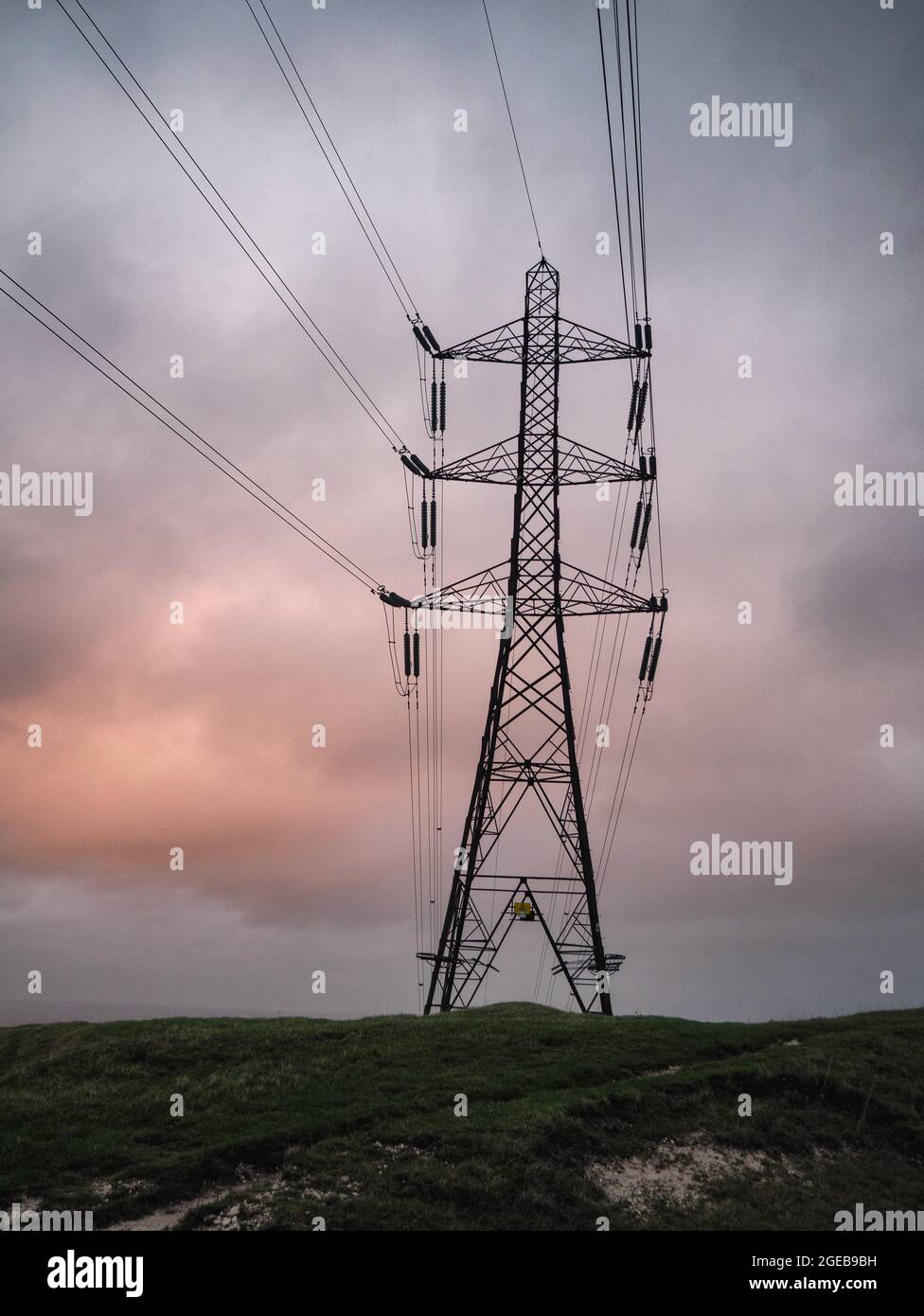 Hill top pylon and powerlines at sunset Stock Photo - Alamy