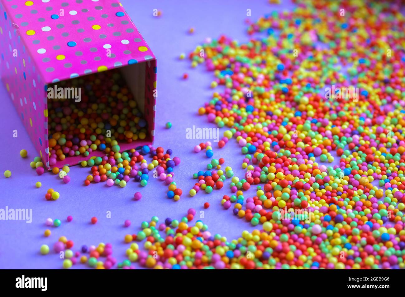 A pink polka dot gift box flatly, lots of multi-colored foam beads of ...