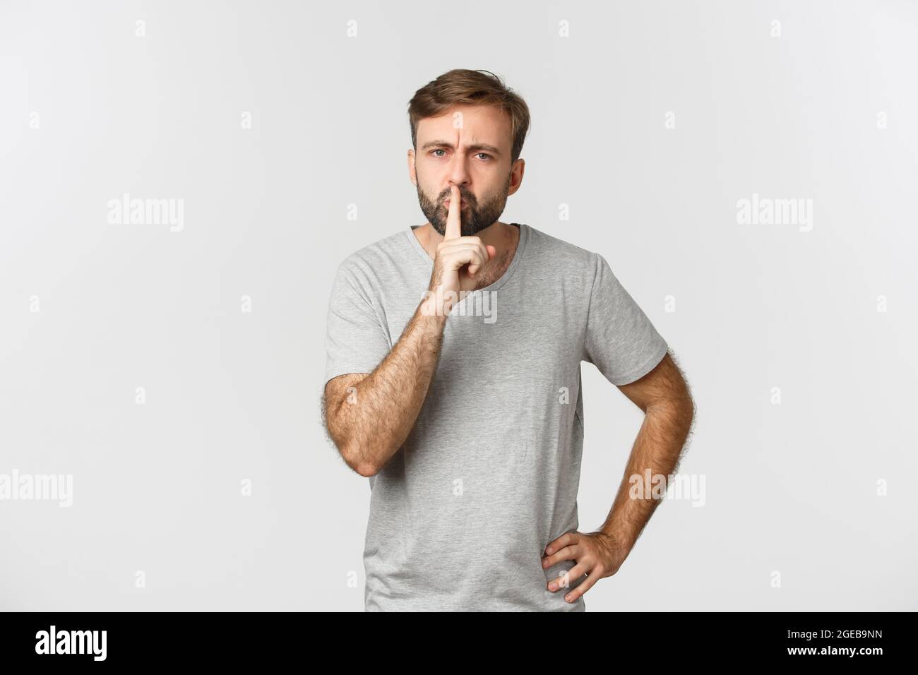 Angry bearded man in grey t-shirt, hushing and frowning, scolding ...