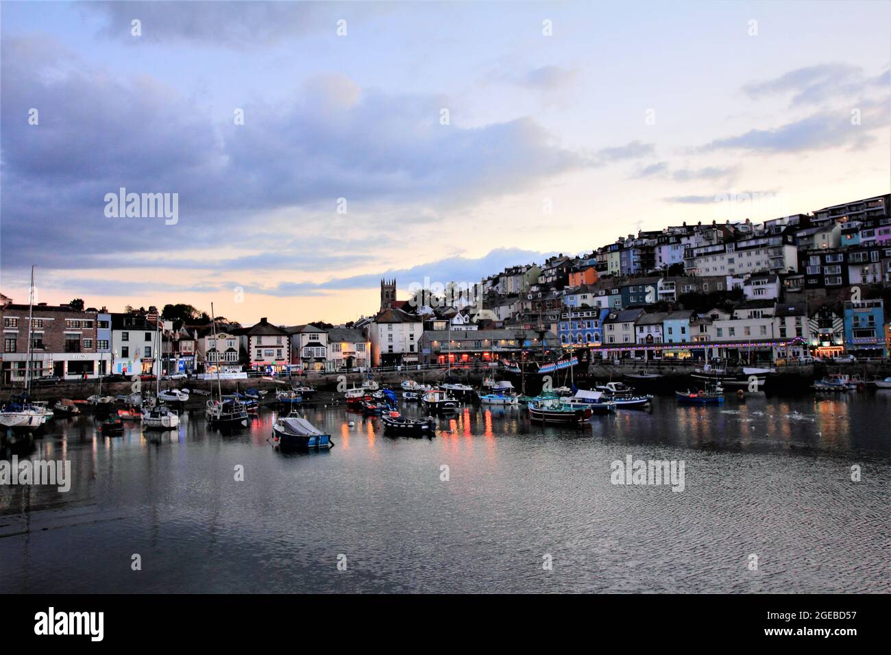 Brixham harbour at twilight with the coloured lights of shops and ...