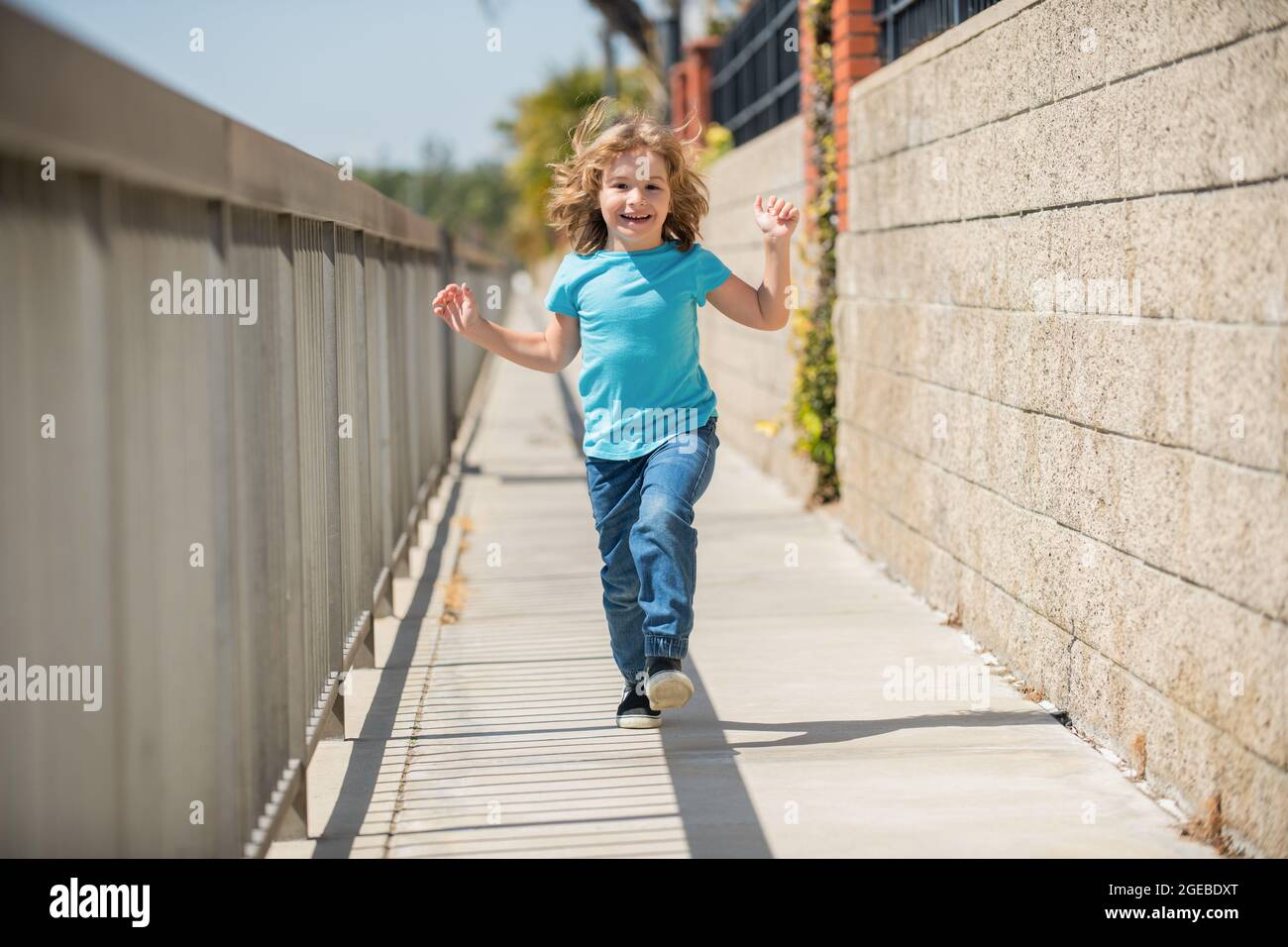 Childhood play. Happy boy have fun running on promenade. Outdoor play ...