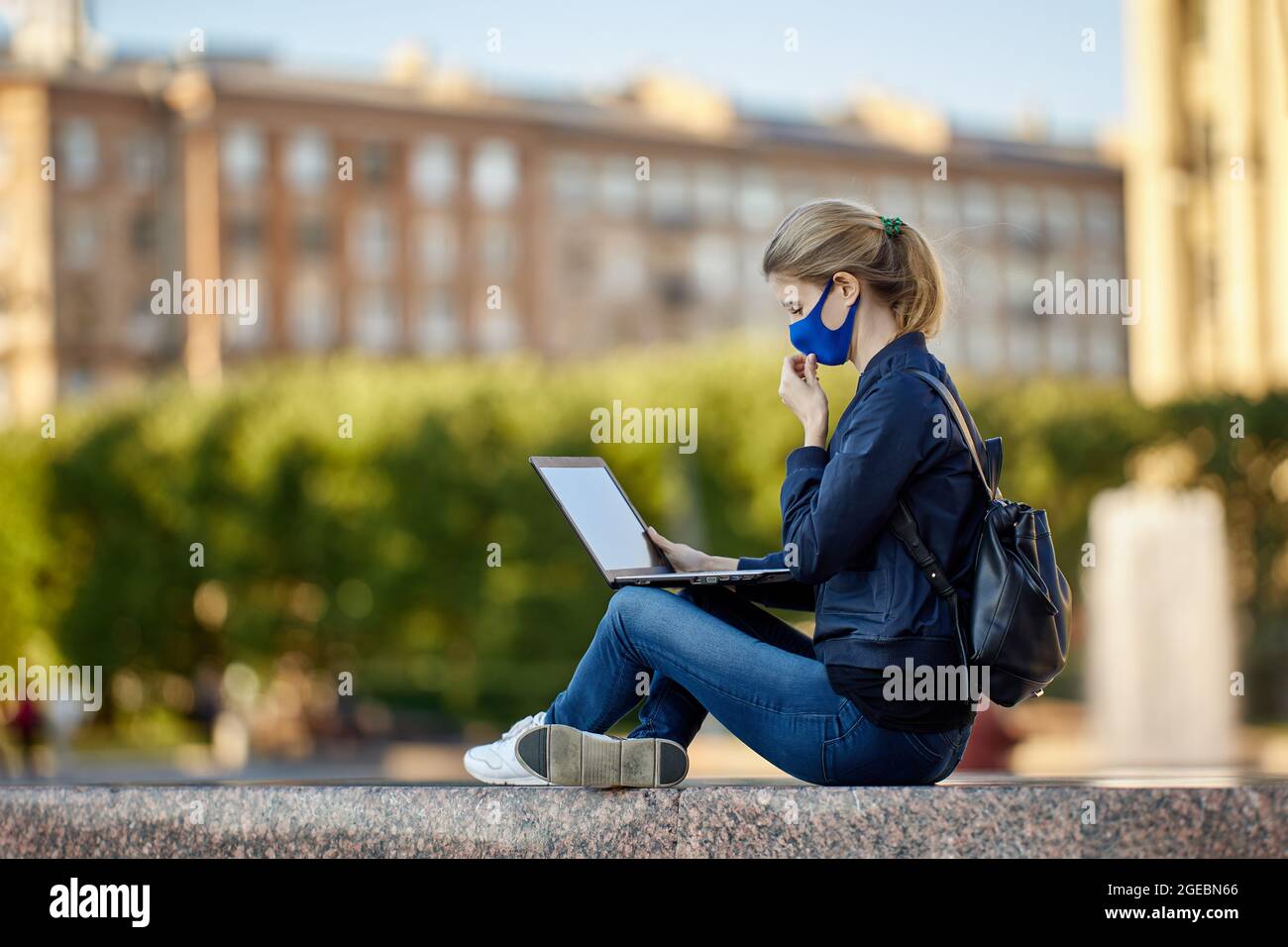 Woman in facial mask with laptop sits in park Stock Photo - Alamy