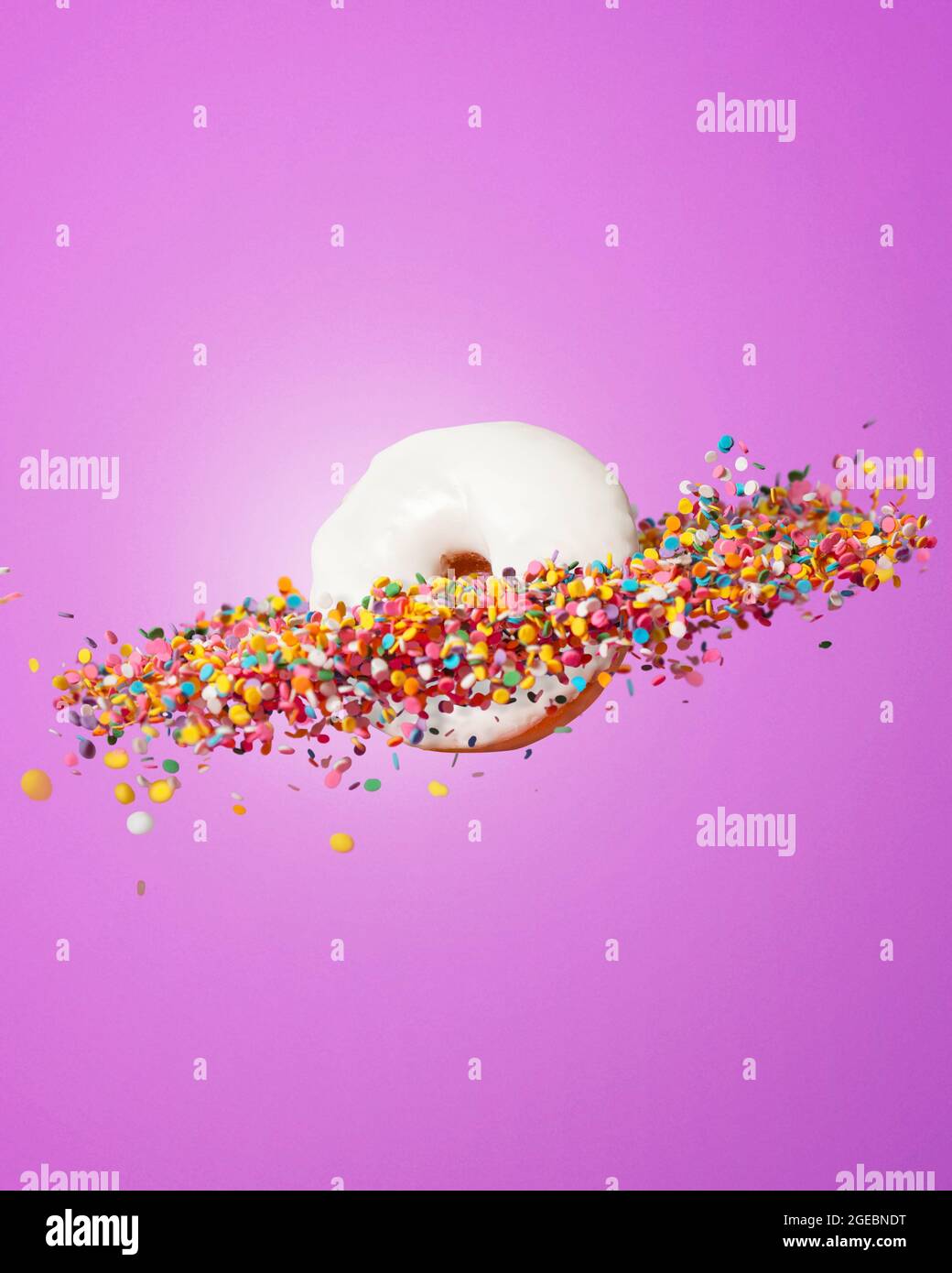 A white-glazed donut with a ring of multi-colored sprinkles as if it ...