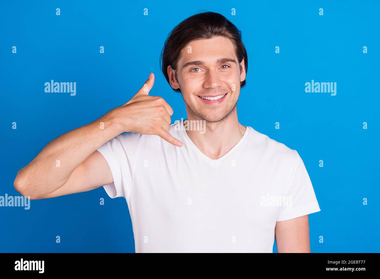 Photo of young happy positive cheerful man hold hands make call me sign ...