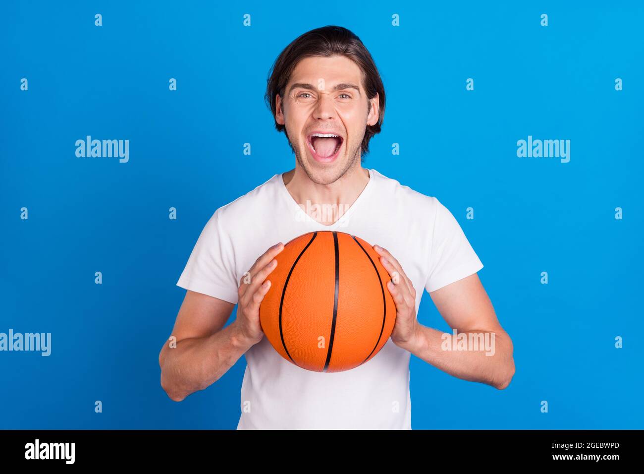 Photo portrait brunet man keeping ball shouting loud in white t-shirt ...