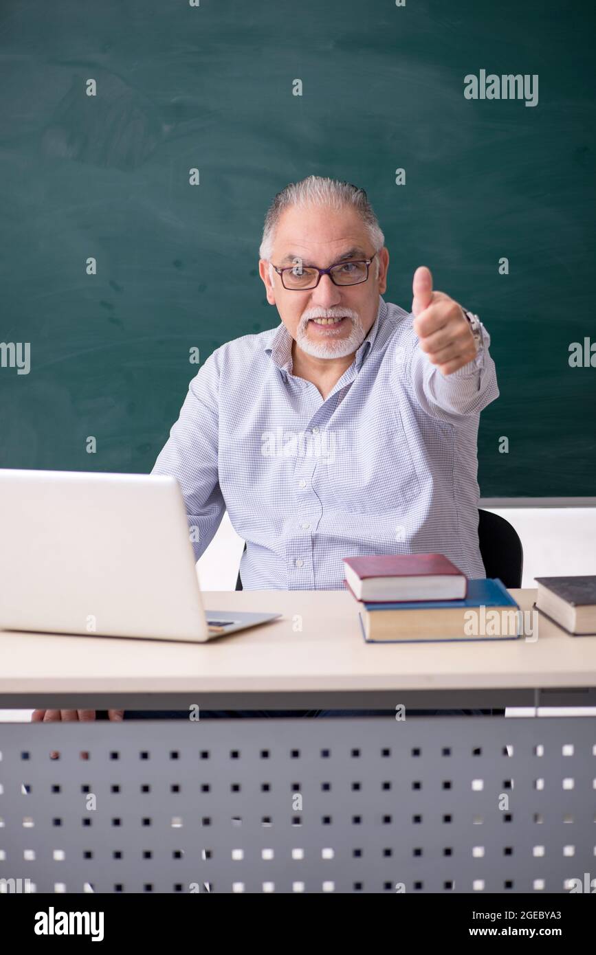 Old teacher in front of green board Stock Photo - Alamy