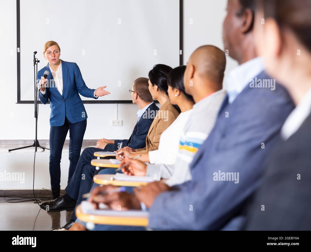 Emotional female business coach leading discussion in conference hall ...