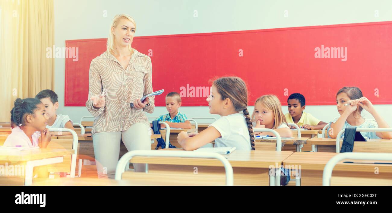 Woman teacher talking with pupils at classroom Stock Photo - Alamy