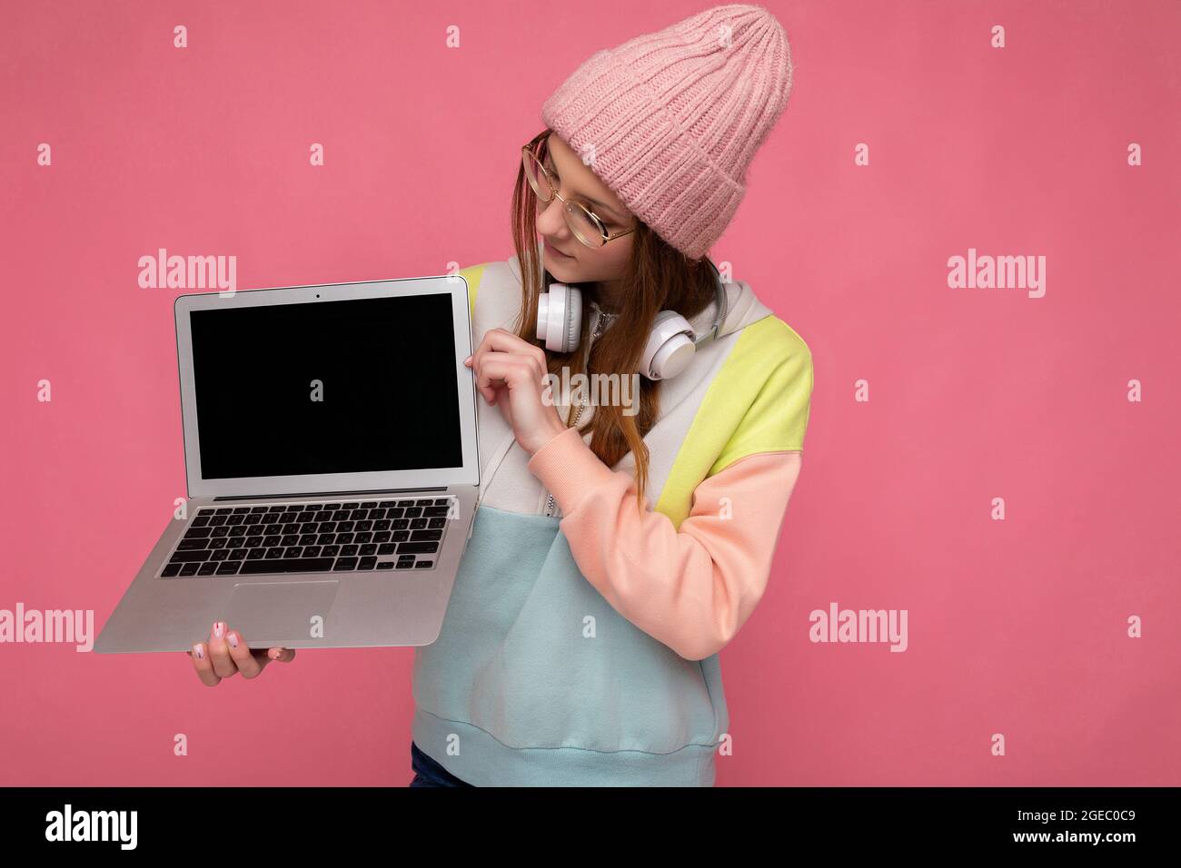 Pretty young woman wearing hat colorful sweater and glasses holding ...