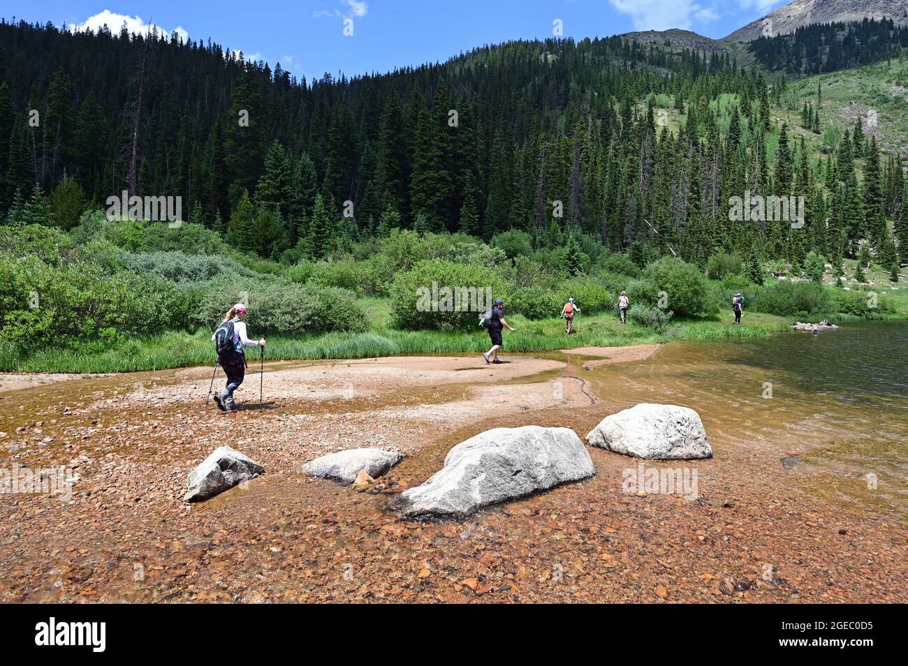 Hikers cross shallow water of Upper Urad Reservoir on Hassell Lake ...
