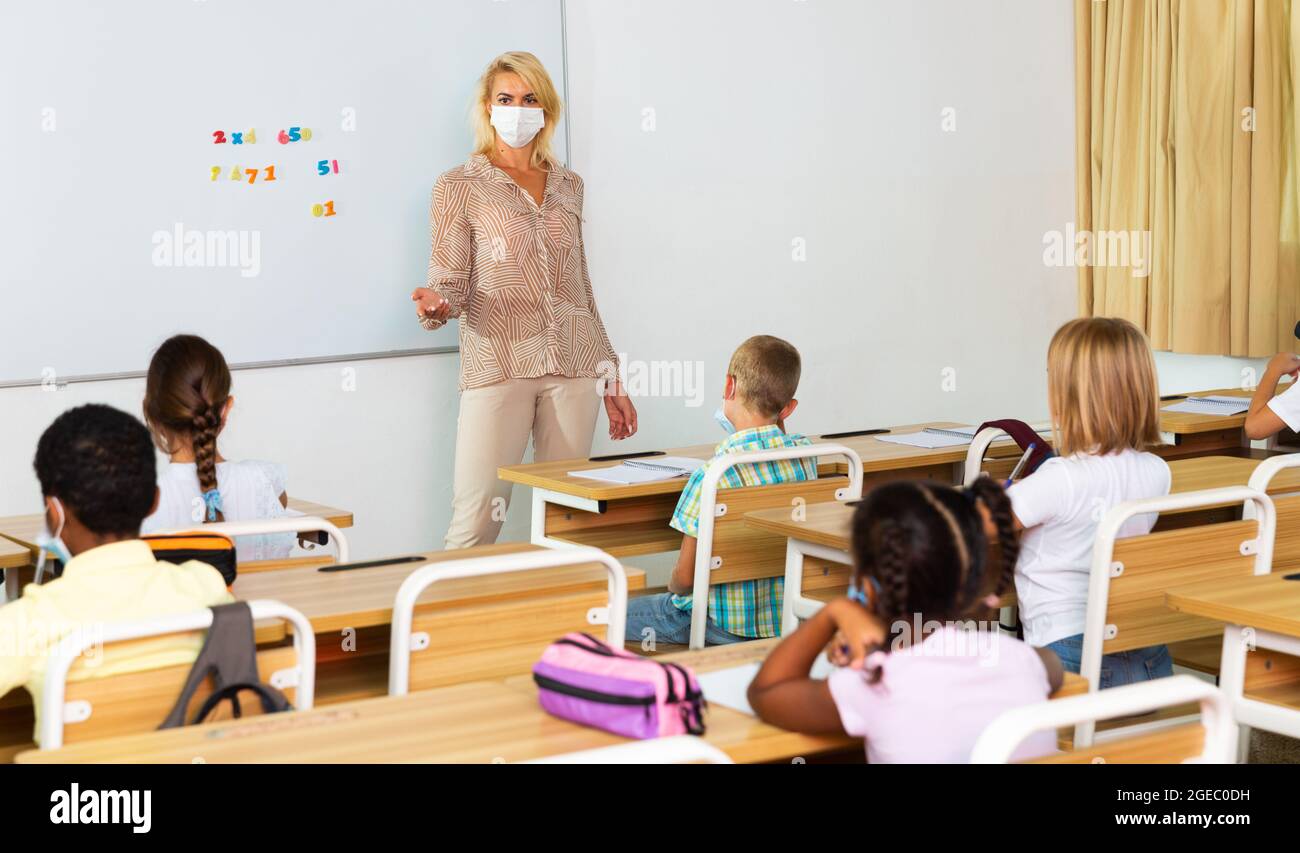 Female teacher in protective mask is giving lecture for primary school ...