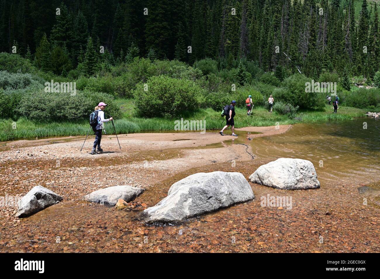 Hikers cross shallow water of Upper Urad Reservoir on Hassell Lake ...