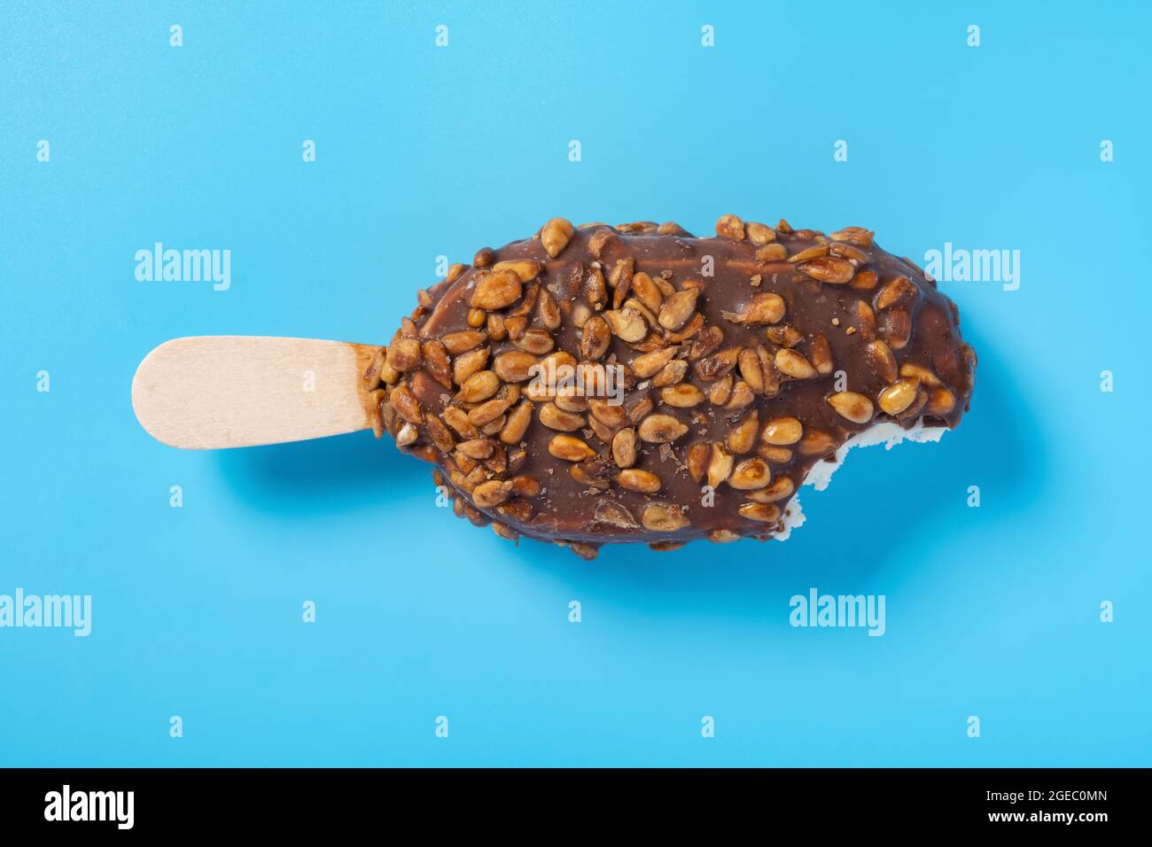 top view chocolate outer popsicle with melon seeds with a bite on blue ...