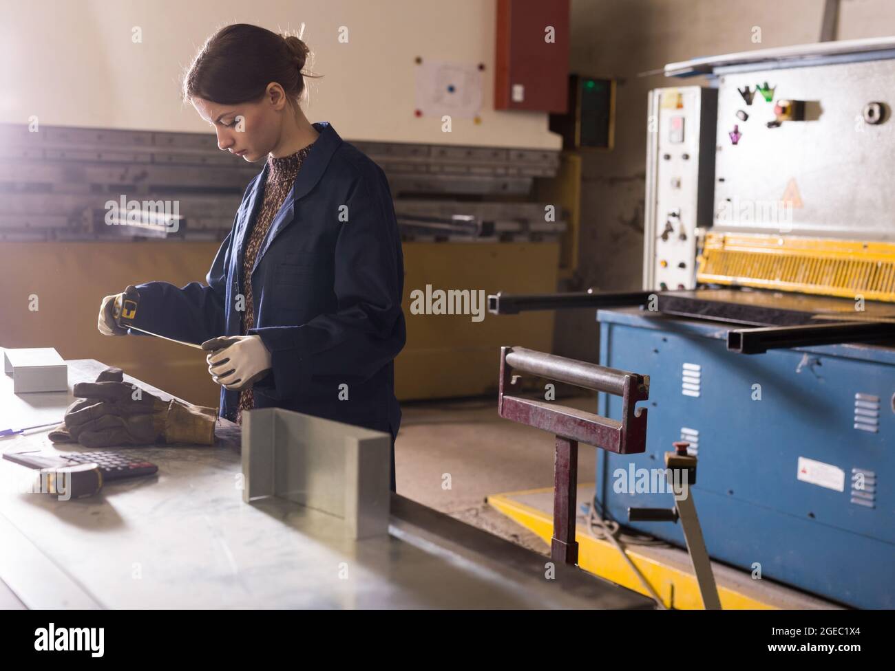 Workwoman measuring metal parts in workshop Stock Photo - Alamy