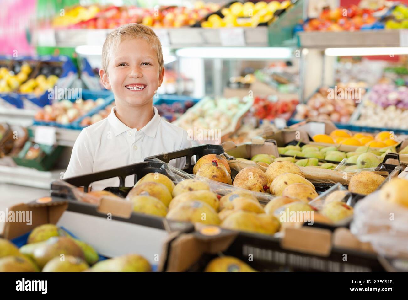 Portrait of cheerful little boy choosing fruits at store Stock Photo ...