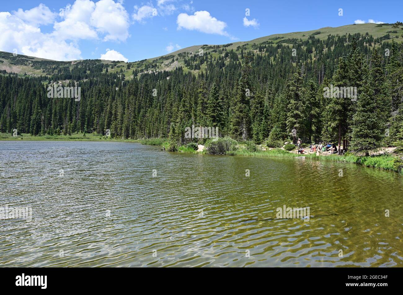 Distant hikers enjoy view of Hassell Lake in Arapaho National Forest ...