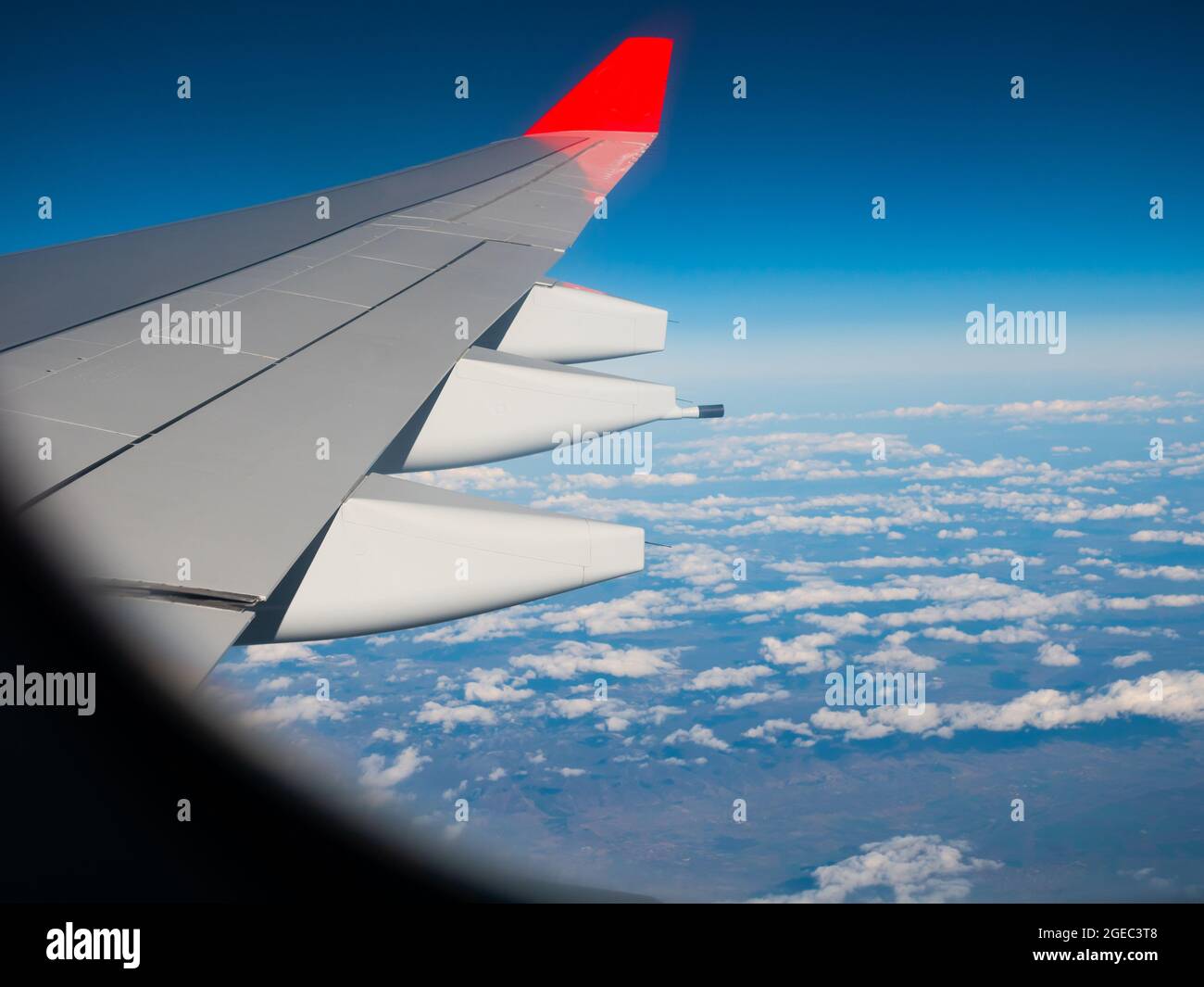 Wing of flying plane from passenger cabin window in blue sky Stock ...