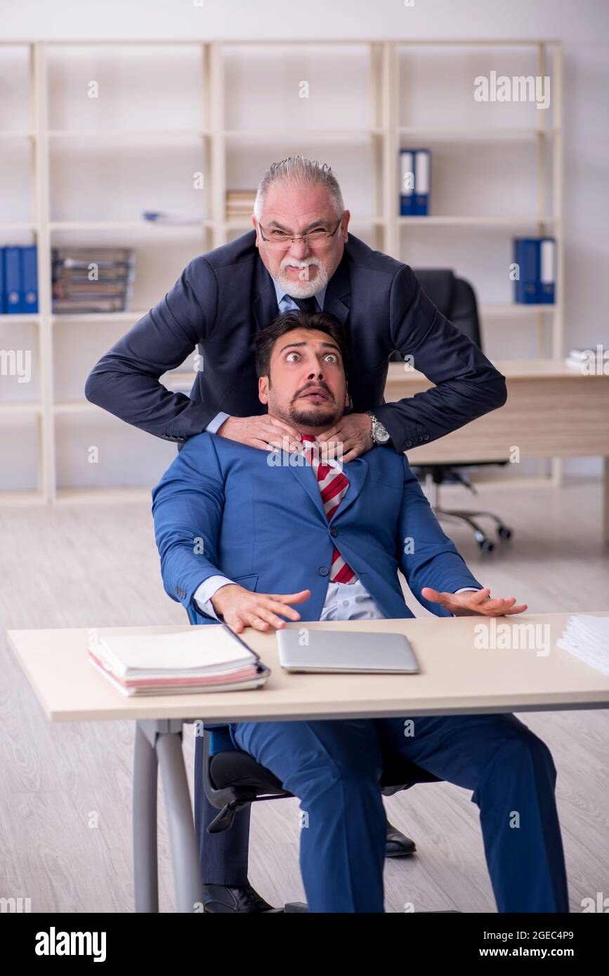 Old boss and young employee in bullying concept Stock Photo - Alamy