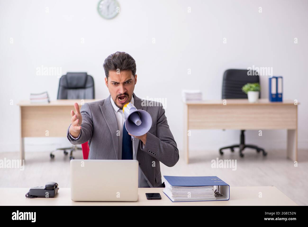 Young businessman employee holding megaphone at workplace Stock Photo ...