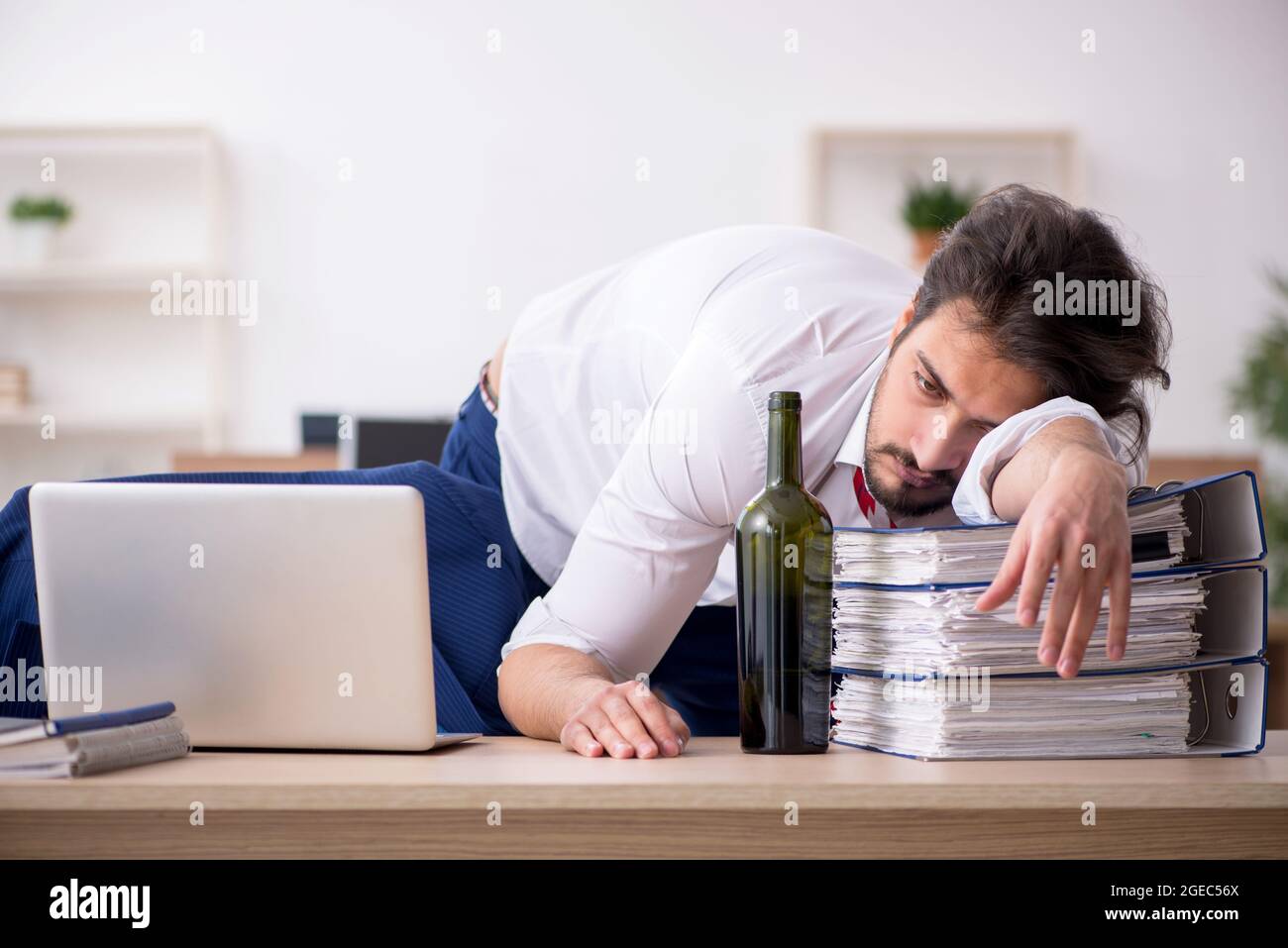 Young alcohol addicted businessman employee working in the office Stock ...