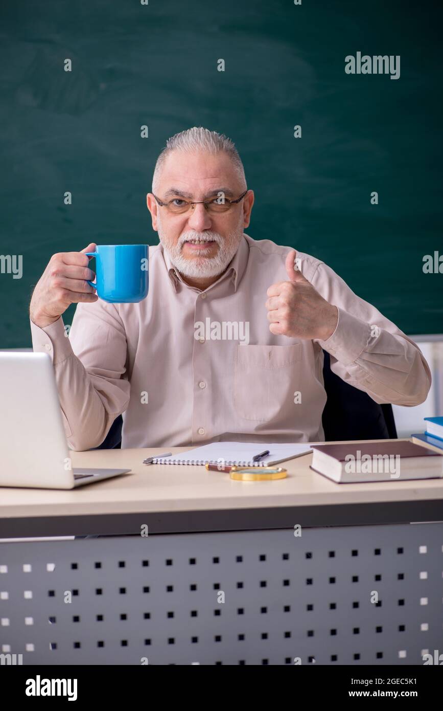 Old teacher drinking coffee in the classroom Stock Photo - Alamy