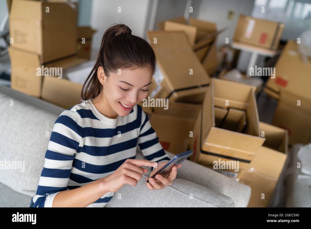 Homeowner Asian woman using cellphone mobile phone for indoor mess with ...
