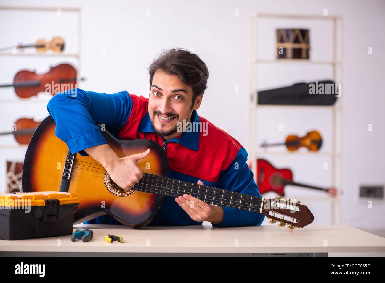 Young repairman repairing musical instruments at workplace Stock Photo ...