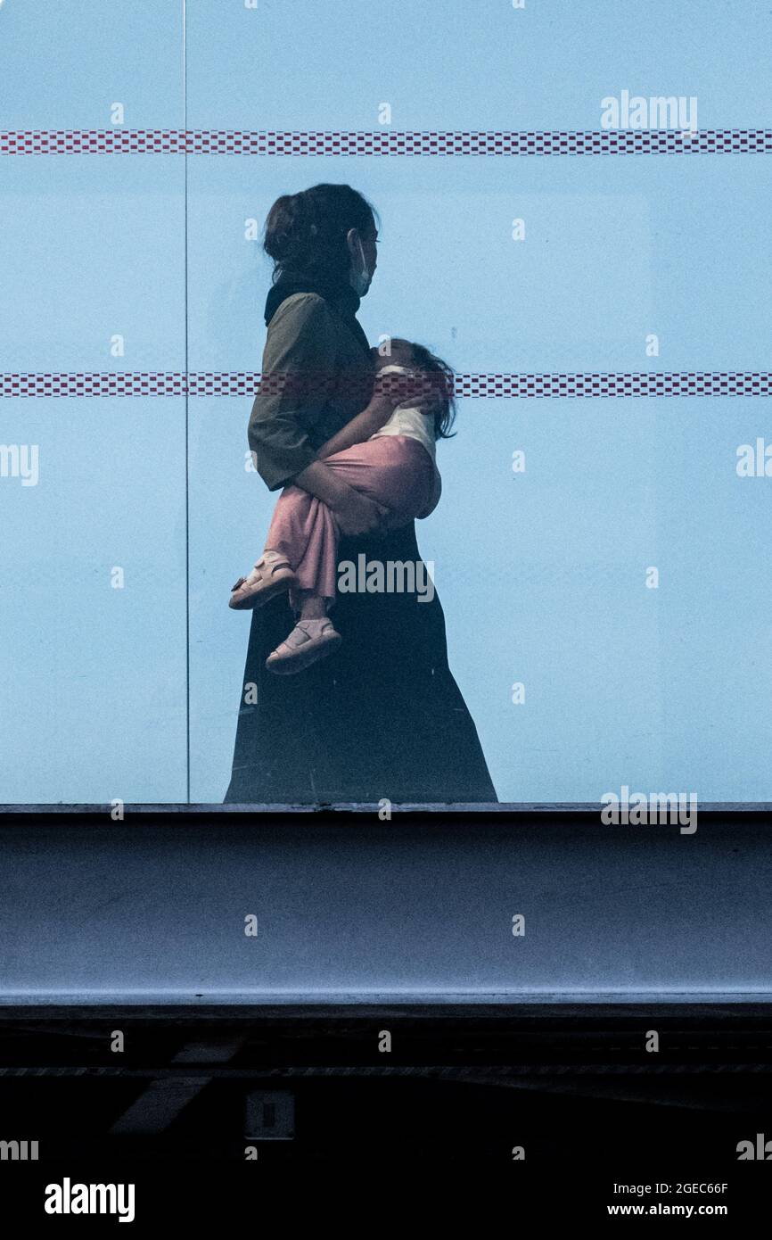 A woman carries a sleeping young girl along with passengers, who fled ...