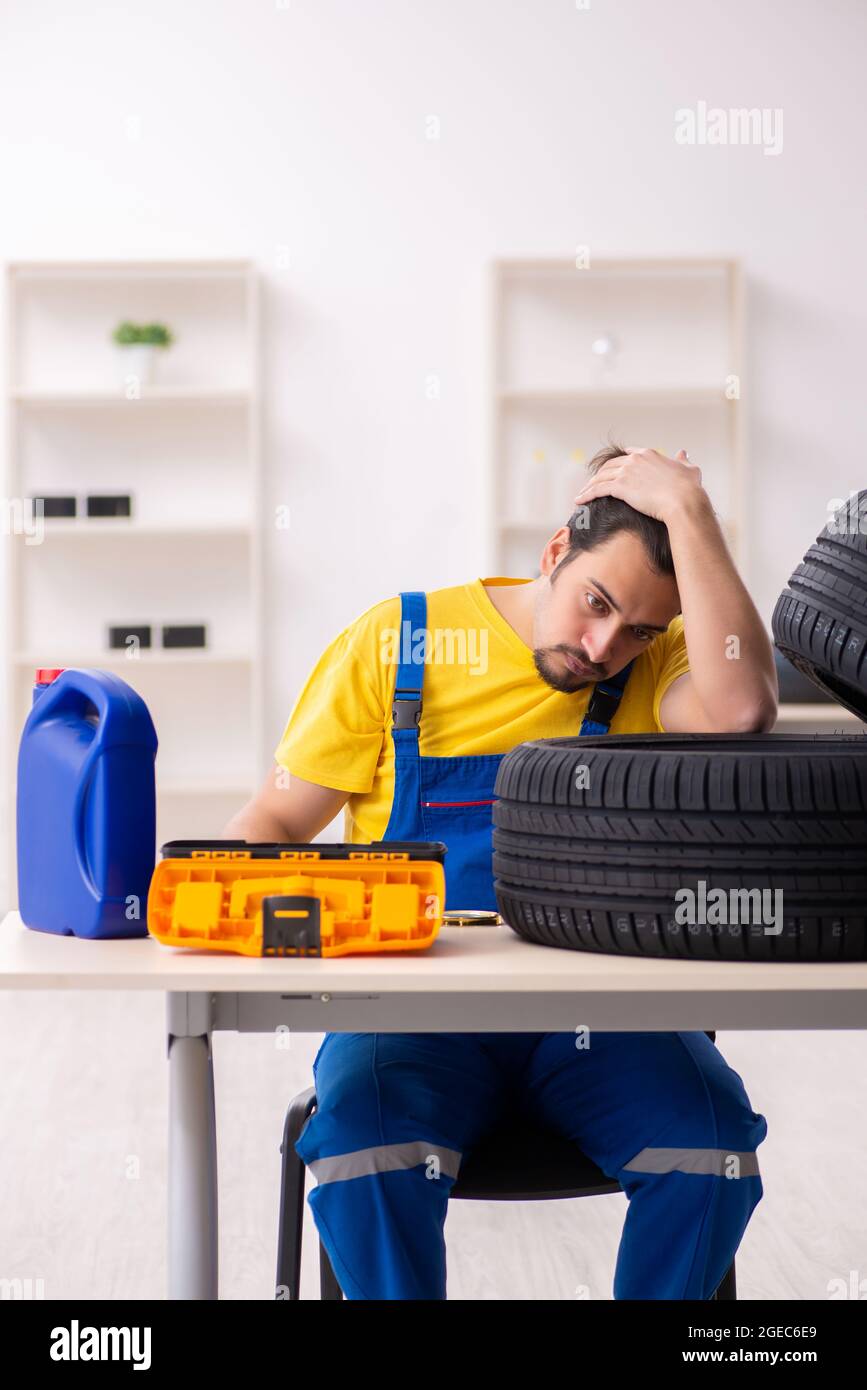 Young garage worker with tyre at workshop Stock Photo - Alamy