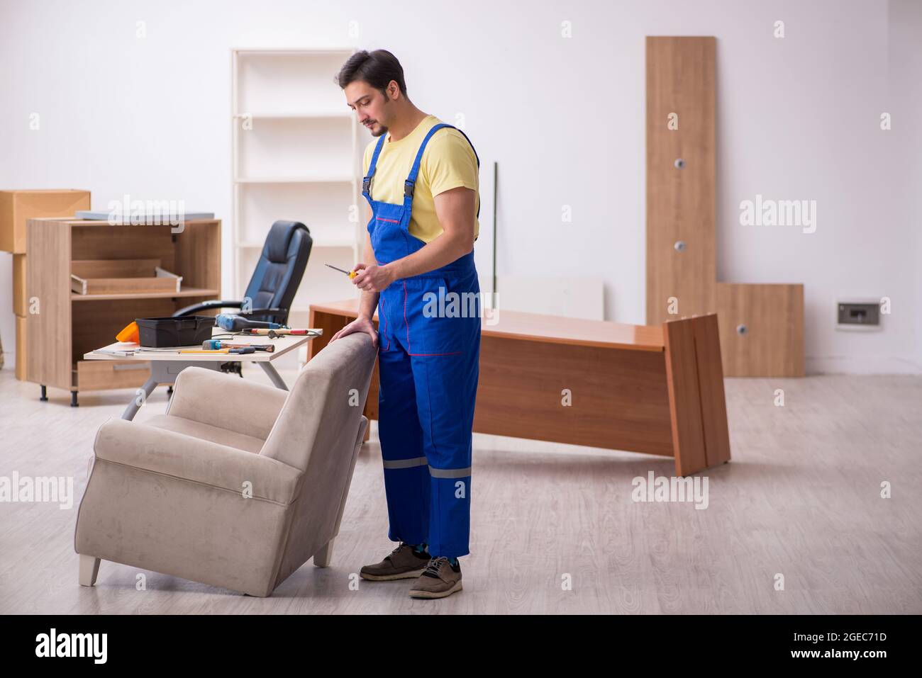 Young carpenter repairing arm-chair in the office Stock Photo - Alamy