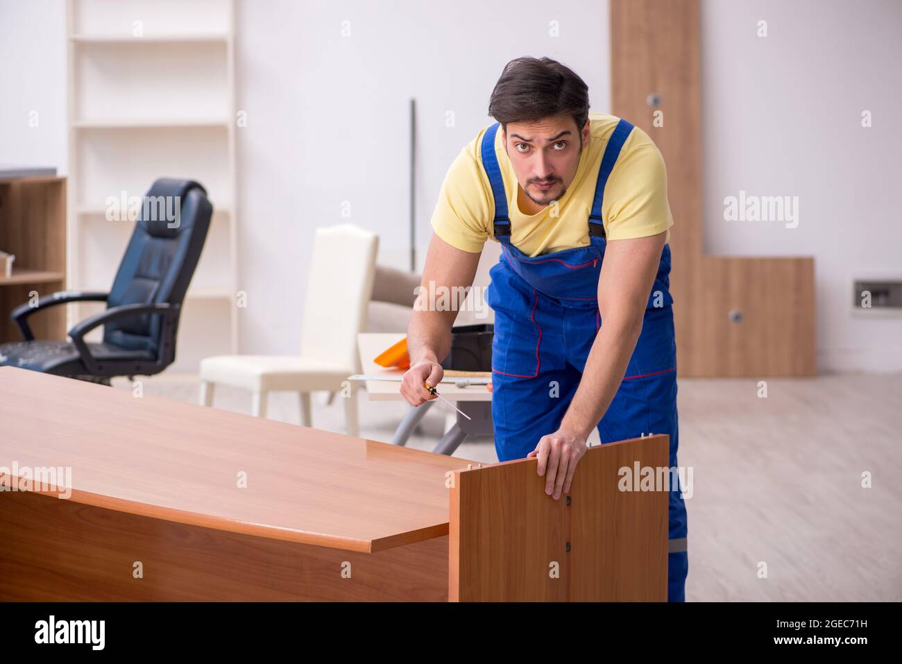 Young carpenter repairing desk in the office Stock Photo - Alamy