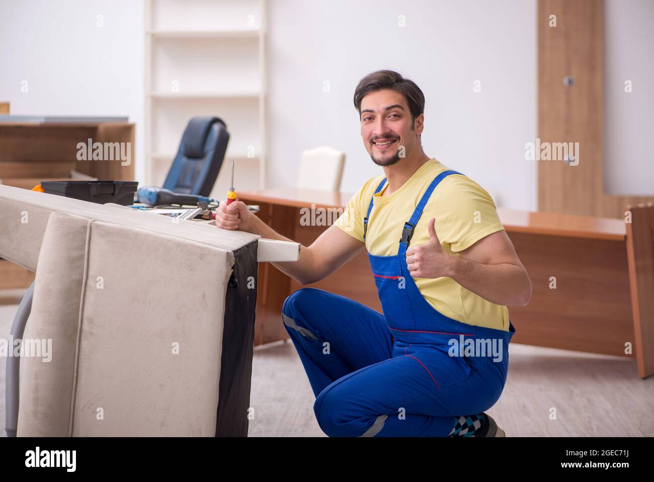 Young carpenter repairing arm-chair in the office Stock Photo - Alamy