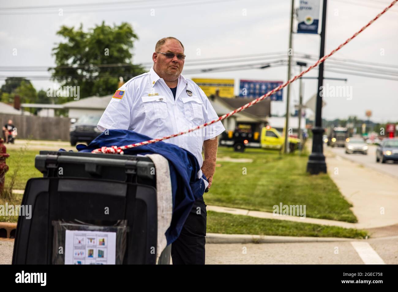 A firefighter waits to help raise an American flag for the funeral ...