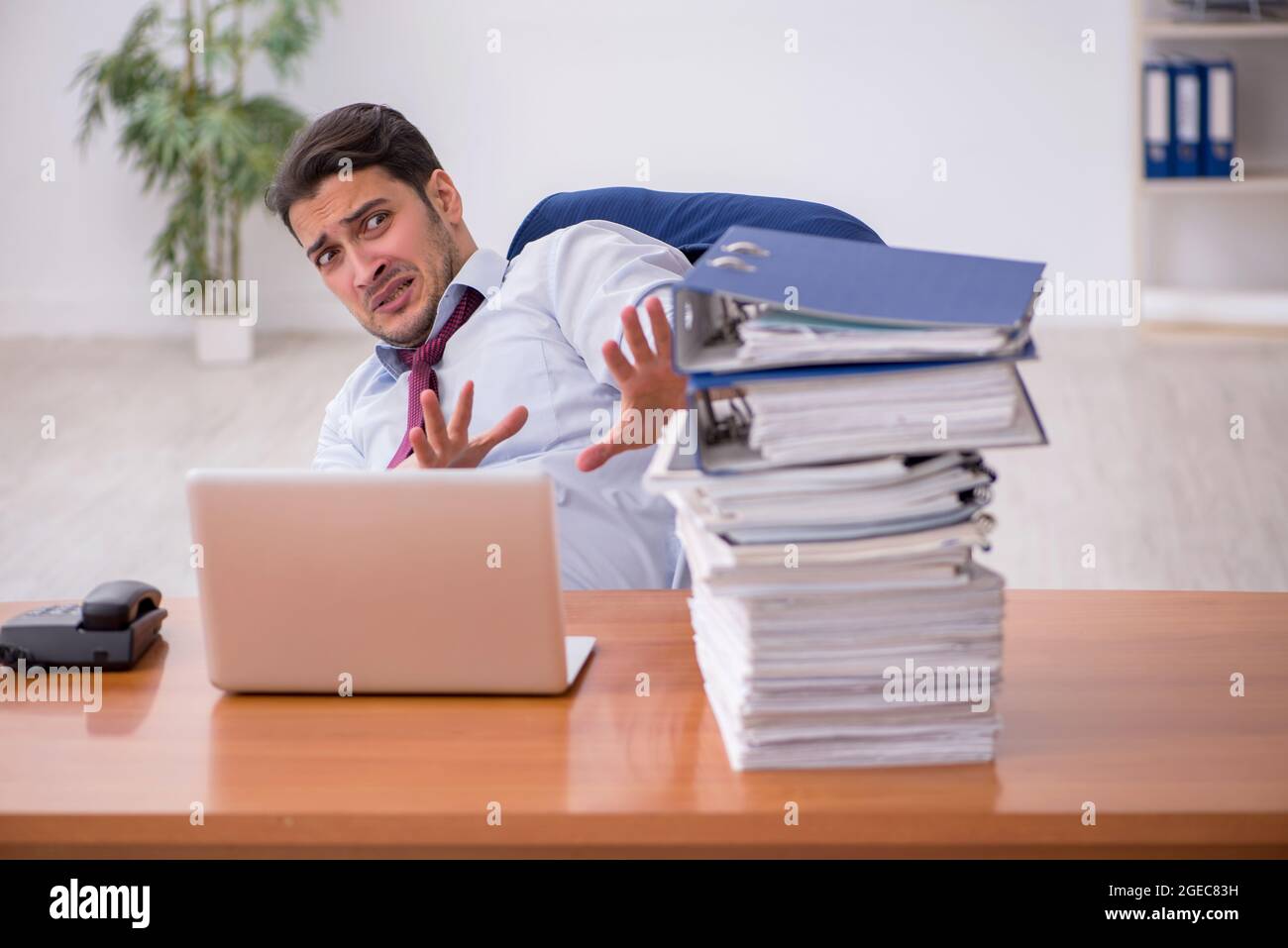 Young male employee and too much work in the office Stock Photo - Alamy