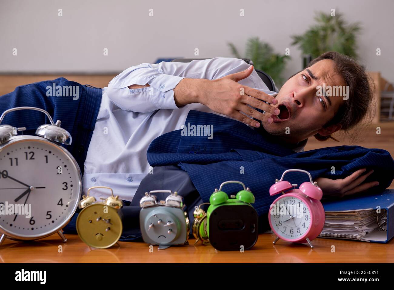 Young businessman sleeping in the office in time management concept ...