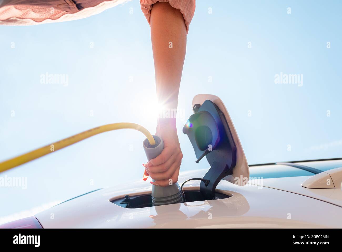 Low angle shot of a Caucasian woman opening an electric car charging ...