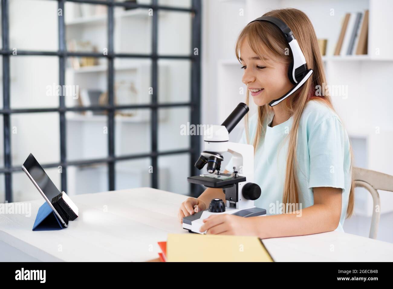 Young girl using microscope during online lesson education at home ...