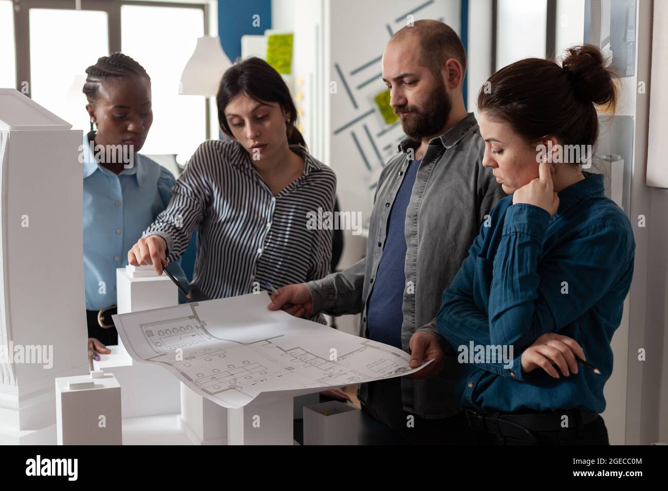 Team of multi ethnic architects designing blueprint plan for ...