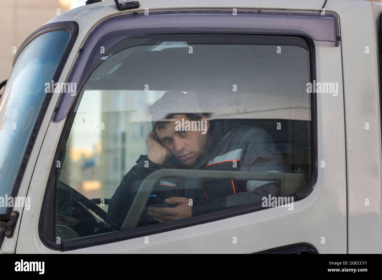 Portrait of a driver in the cabin of a truck driving with a mobile ...