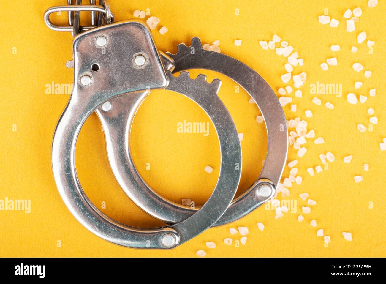 handcuffs and crystal drugs on yellow background, arrest of a drug ...