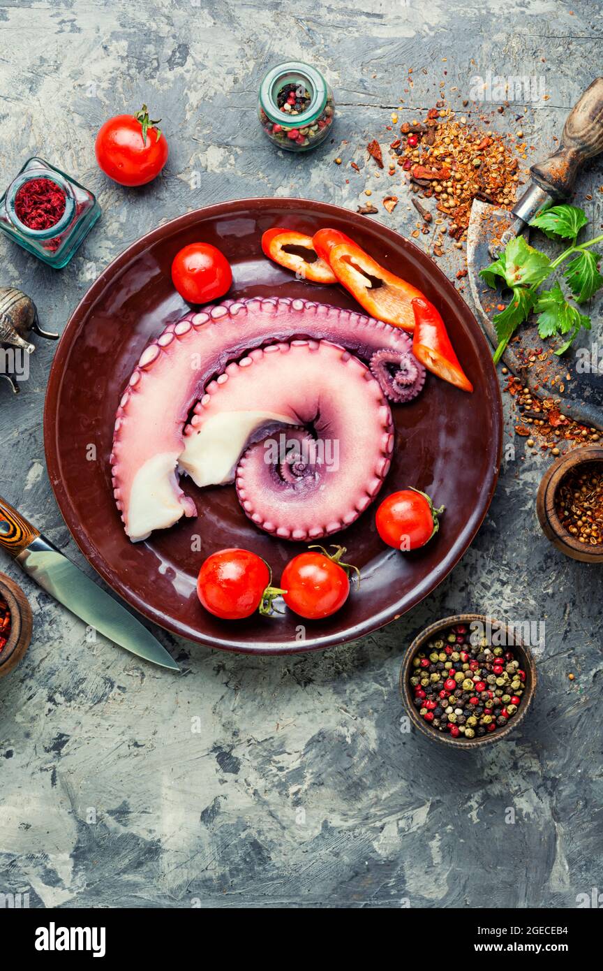 Raw octopus tentacle with vegetables on the kitchen table Stock Photo ...