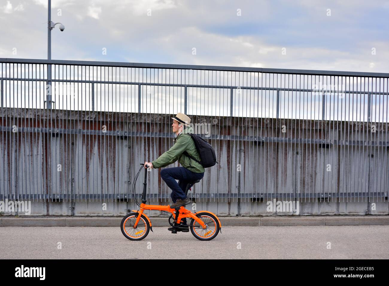 Hipster man in hat rides a bike to work. Cyclist with a backpack rides ...