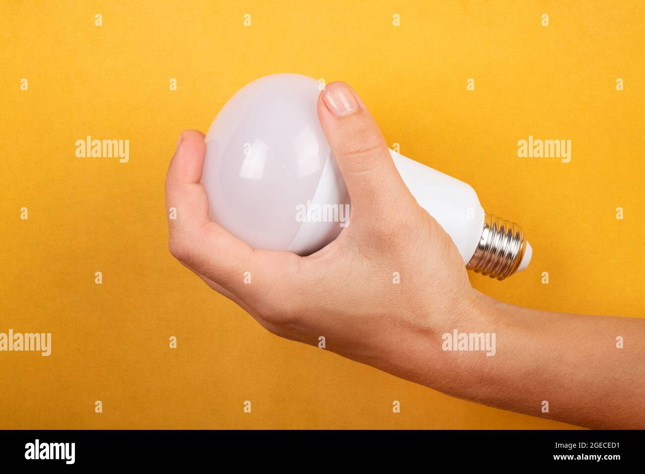energy saving concept, led saving lamp in hand on yellow background ...