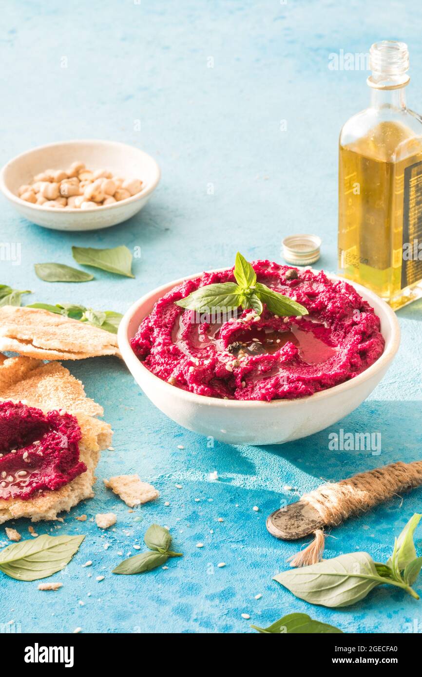 red beetroot hummus on blue background, lemon, sesame, olive oil, pita ...
