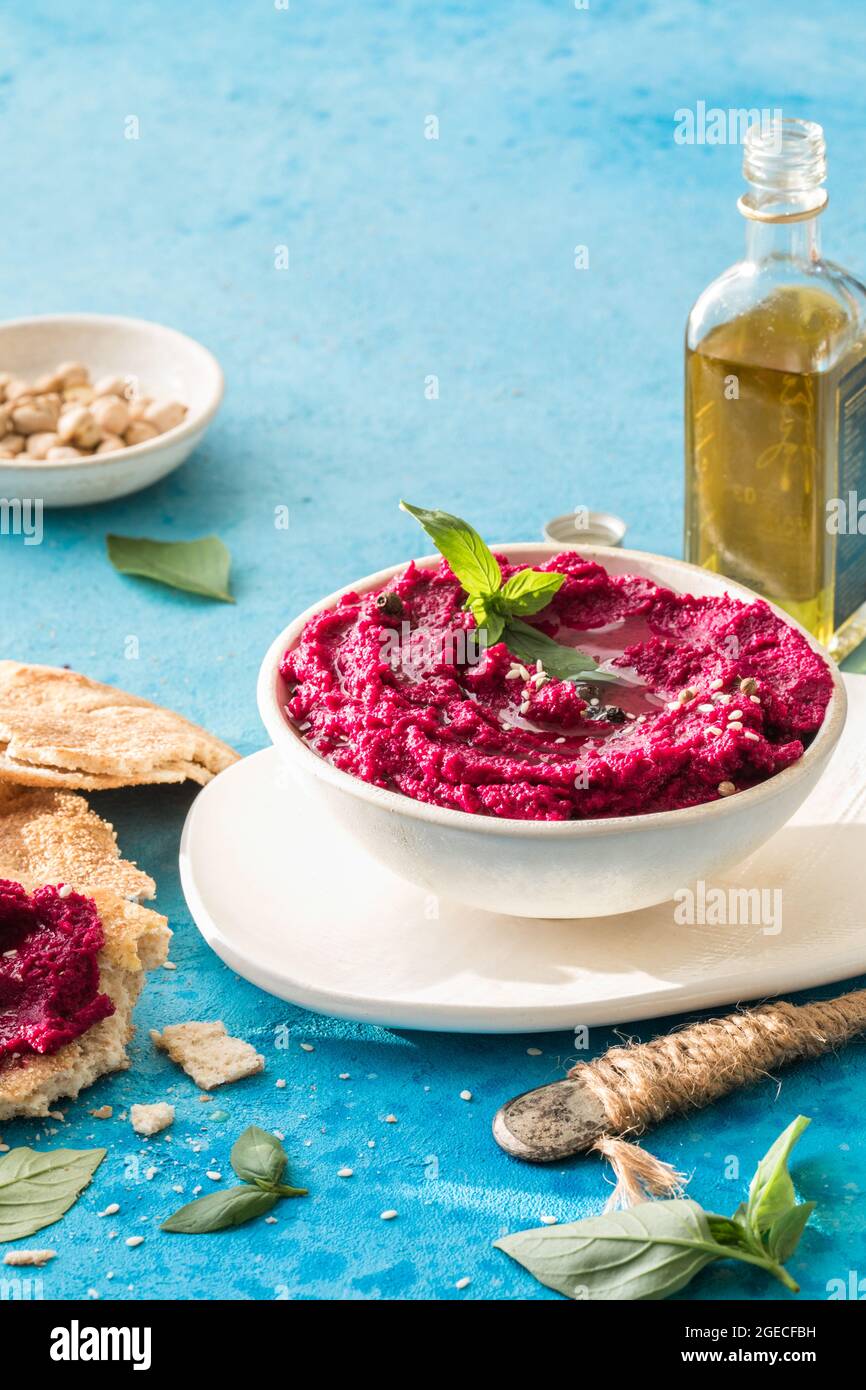 red beetroot hummus on blue background, lemon, sesame, olive oil, pita ...