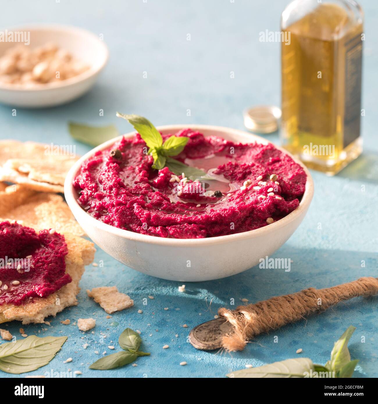 red beetroot hummus on blue background, lemon, sesame, olive oil, pita ...