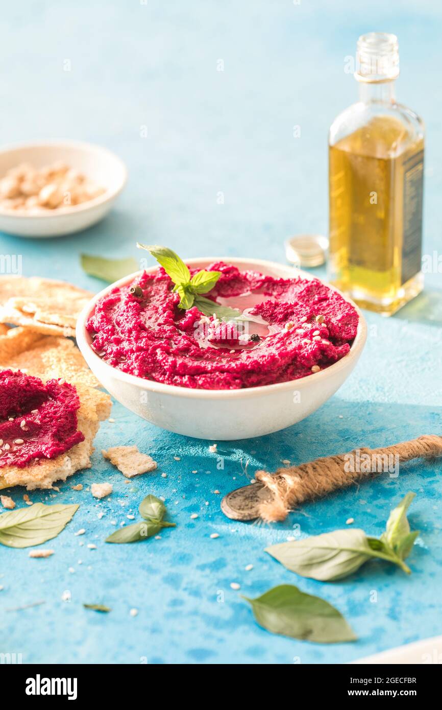 red beetroot hummus on blue background, lemon, sesame, olive oil, pita ...